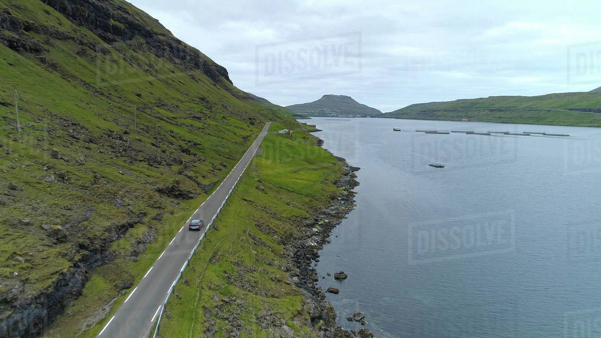 AERIAL: Flying behind a tourist car cruising down an empty asphalt road ...