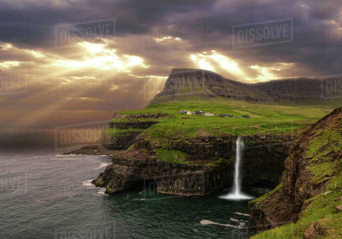 AERIAL: Bright golden sun rays shine through the dense clouds above the ...