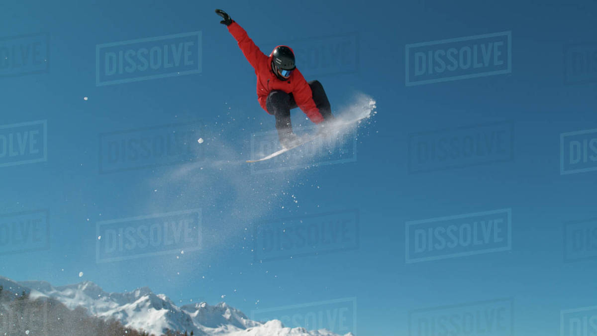 Awesome action shot of male snowboarder leaving a trail of snow while ...