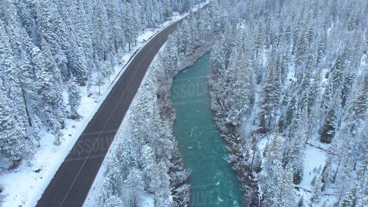 AERIAL: Flying over a beautiful emerald river and scenic asphalt road ...