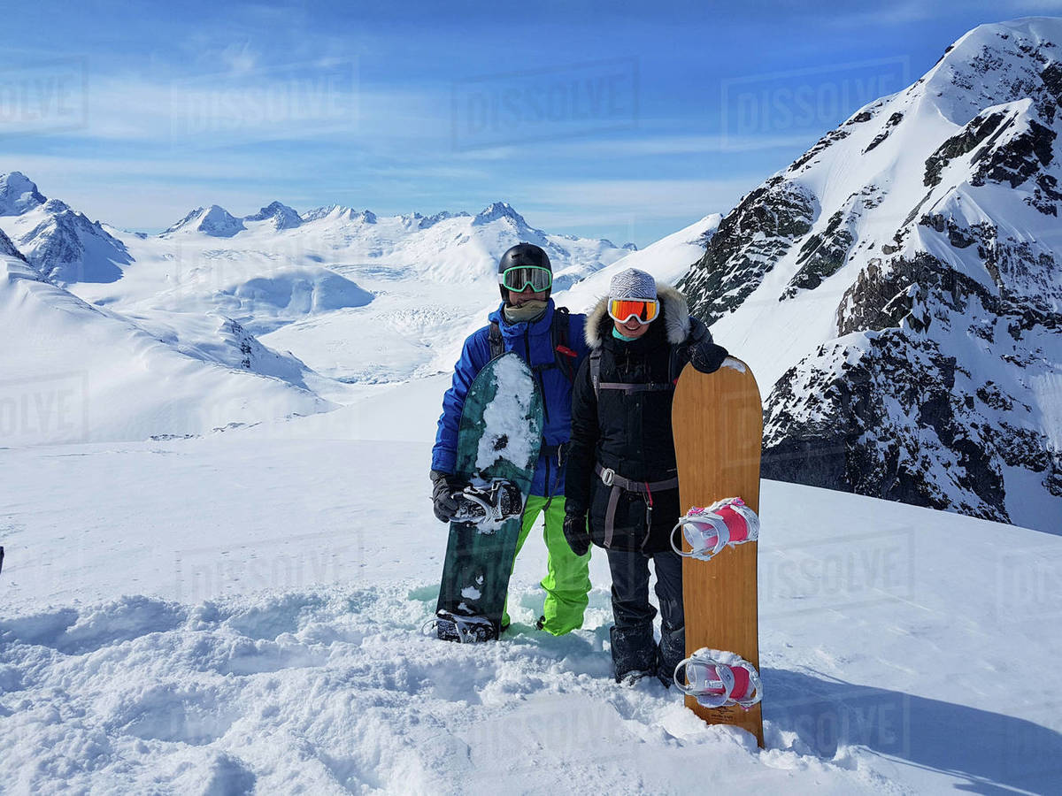 Happy young snowboarder couple poses in spectacular mountains on a ...