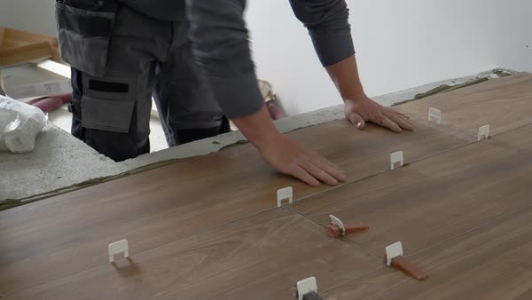CLOSE UP: Tiler places a brown tile on fresh mortar and fastens it with ...