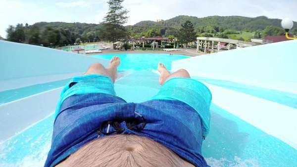Man sliding down extreme fast water slide toboggan on a fun summer day ...