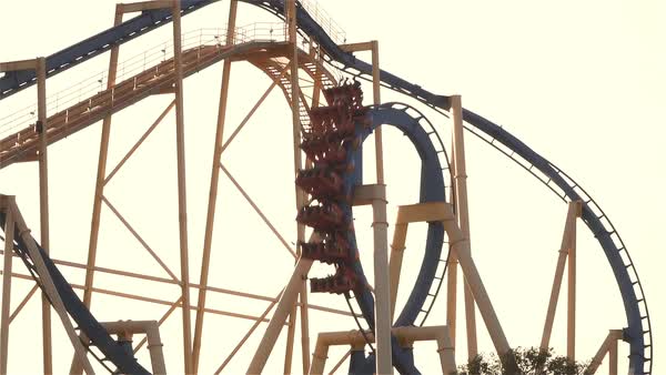Slow motion close-up: people riding extreme roller coaster attraction ...