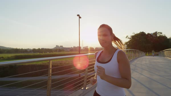 Female running in green park in small suburban town with tall buildings ...