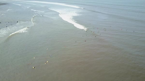Flying above Bali beach with brown foamy ocean water splashing on the ...