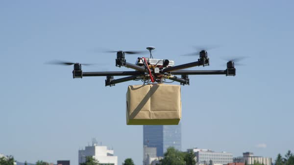 CLOSE UP: UAV drone delivery. Multicopter flying big brown package into ...