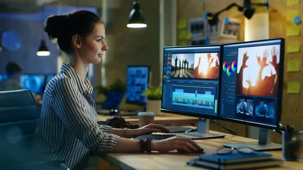 Beautiful female videographer edits footage on her personal computer ...