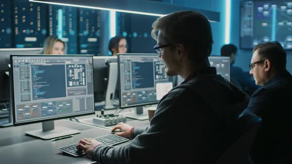 Team of it programers working on desktop computers in data center ...