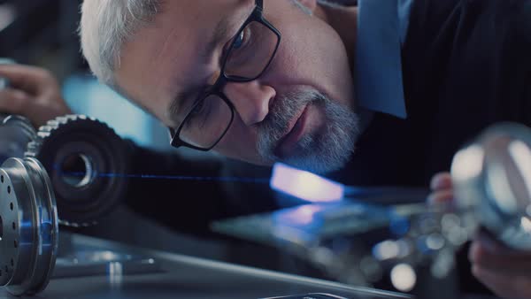 Close-up portrait of focused middle aged engineer in glasses working ...