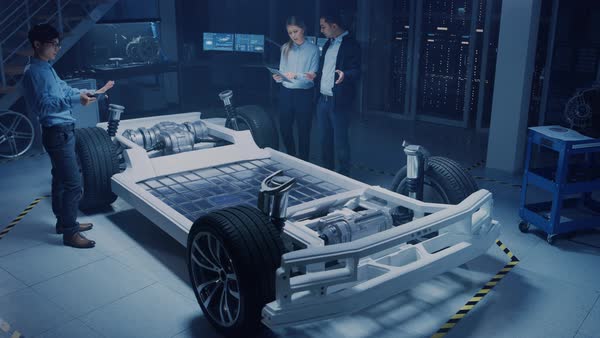 Automotive design engineers talking while working on electric car ...