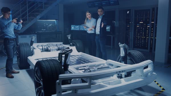 Automotive design engineers talking while working on electric car ...