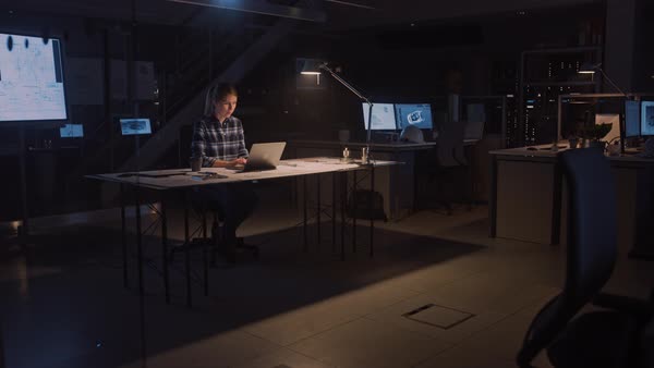 Beautiful female engineer sitting at her desk works on a laptop ...