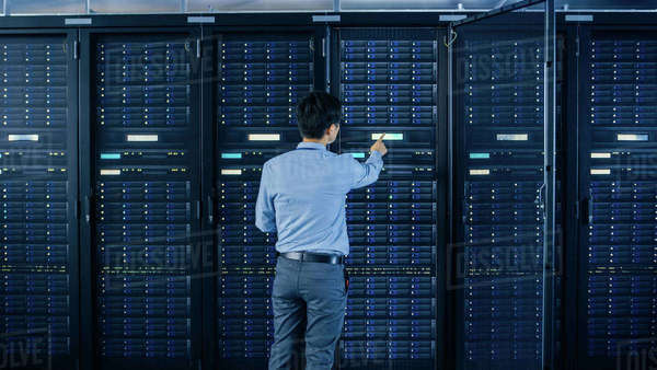 In the Modern Data Center: IT Engineer Standing Beside Open Server Rack ...