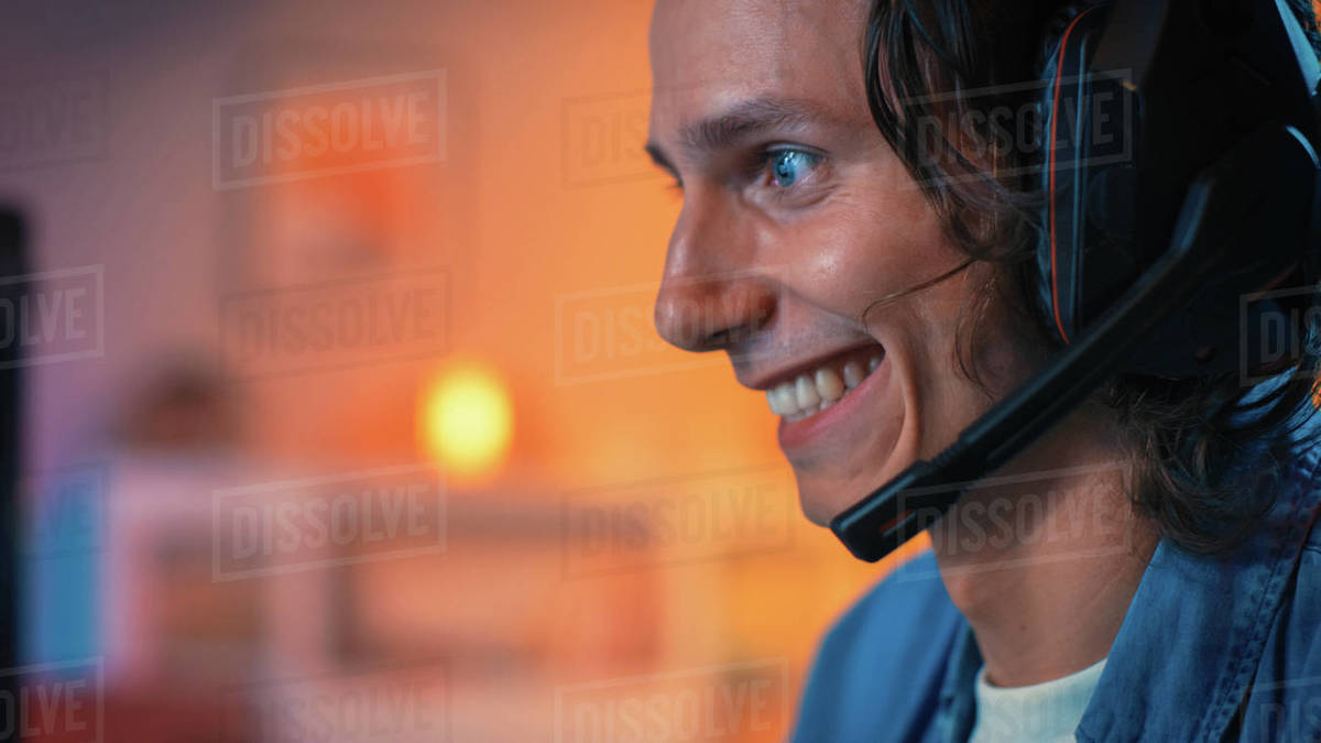 Close up of an excited gamer in headset with a mic playing online video ...