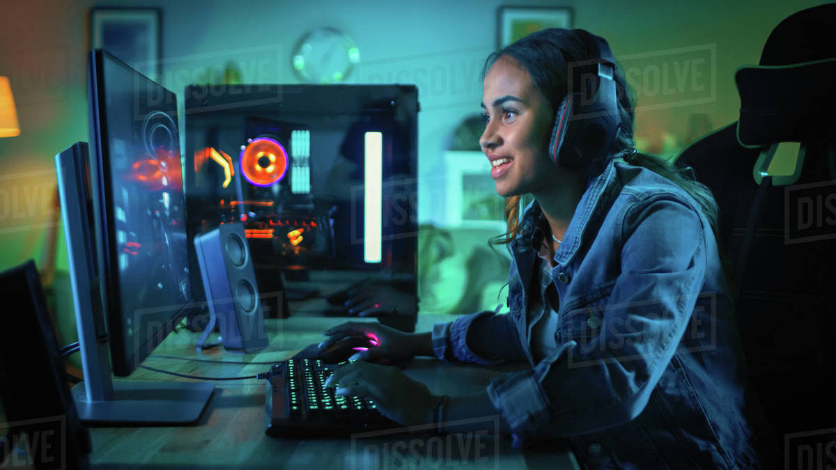 Pretty and excited black gamer girl in headphones is playing first ...