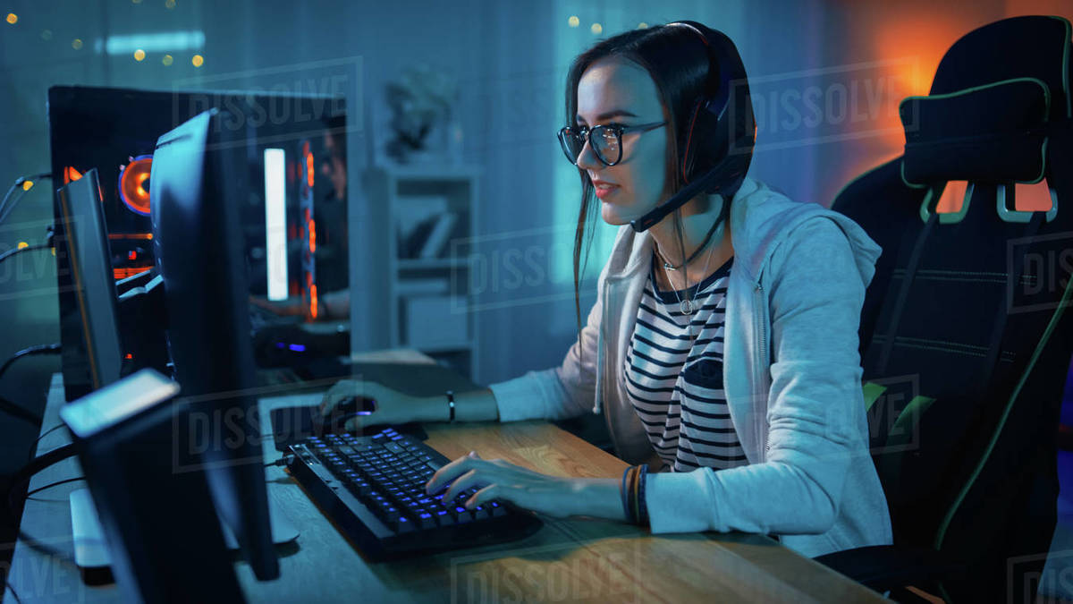 Excited gamer girl in headset with a mic playing online video game on ...