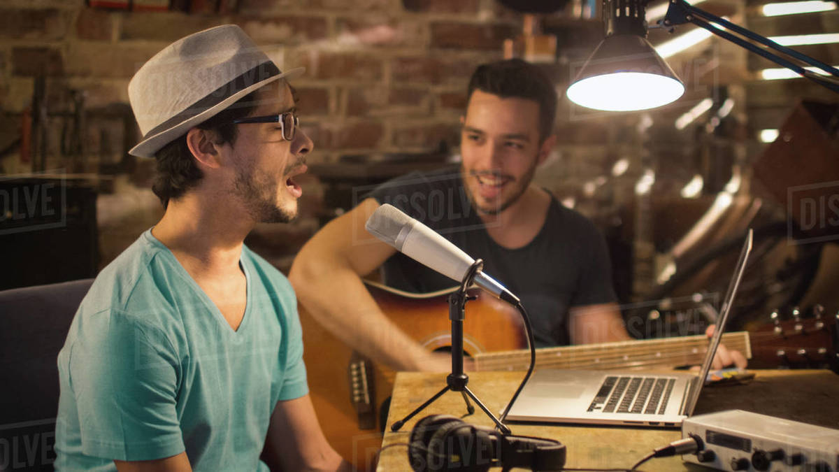 Two young man sing and play guitar while recording a song in a home ...