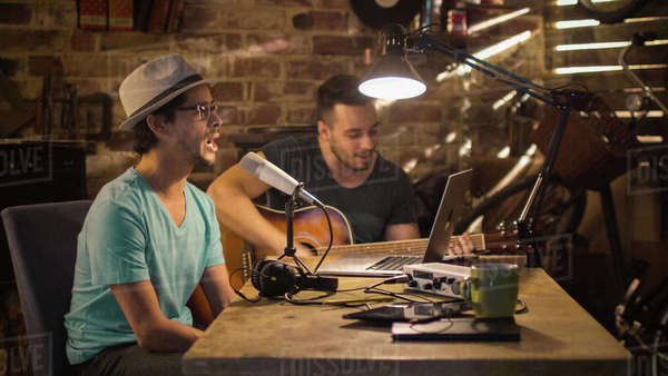 Two young man sing and play guitar while recording a song in a home ...