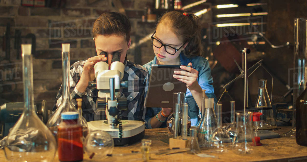 Young boy is making chemistry experiments while girl is looking at a ...