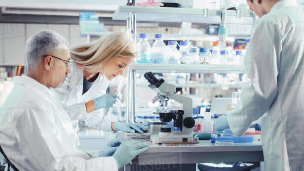 Group of Research Scientists in White Coats are Working with Microscope ...