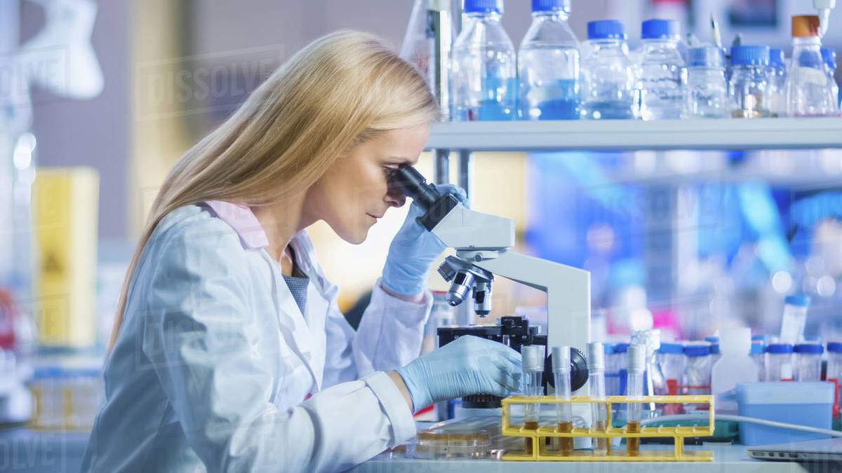 Blonde Female Research Scientist in White Coat is Working With a ...