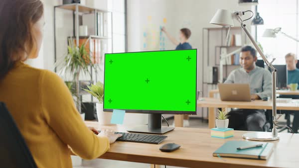 Creative young woman sitting at her desk using desktop computer with ...