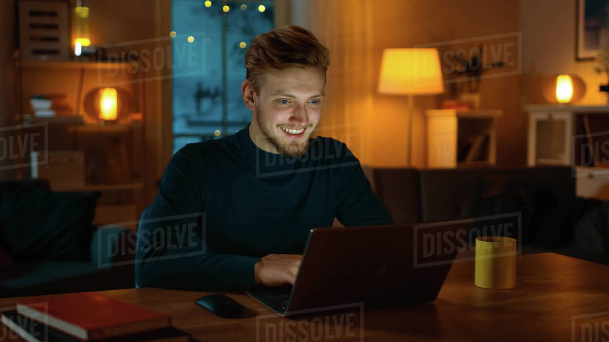 Handsome Smiling Man Works on a Laptop Computer while Sitting at His ...