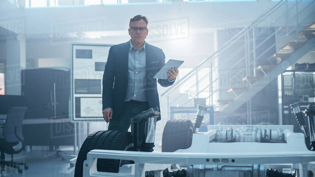 Engineer with Glasses Works on a Tablet Computer Next to an Electric ...