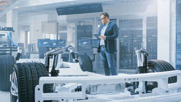 Automotive Design Engineer Looking at Technical Drawing of an Electric ...