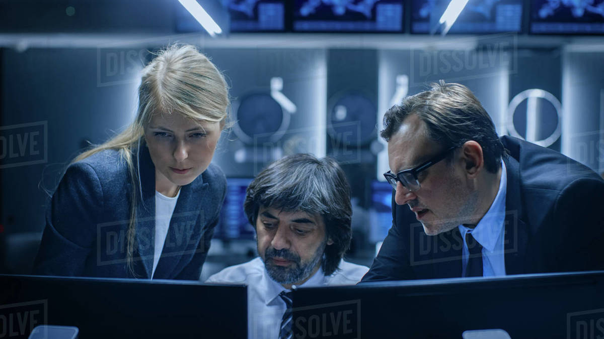 Male and Female Operators Working On Computers in System Control Room ...