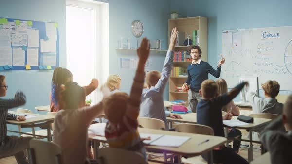 Caring Teacher Explains Lesson to a Classroom Full of Bright Diverse ...