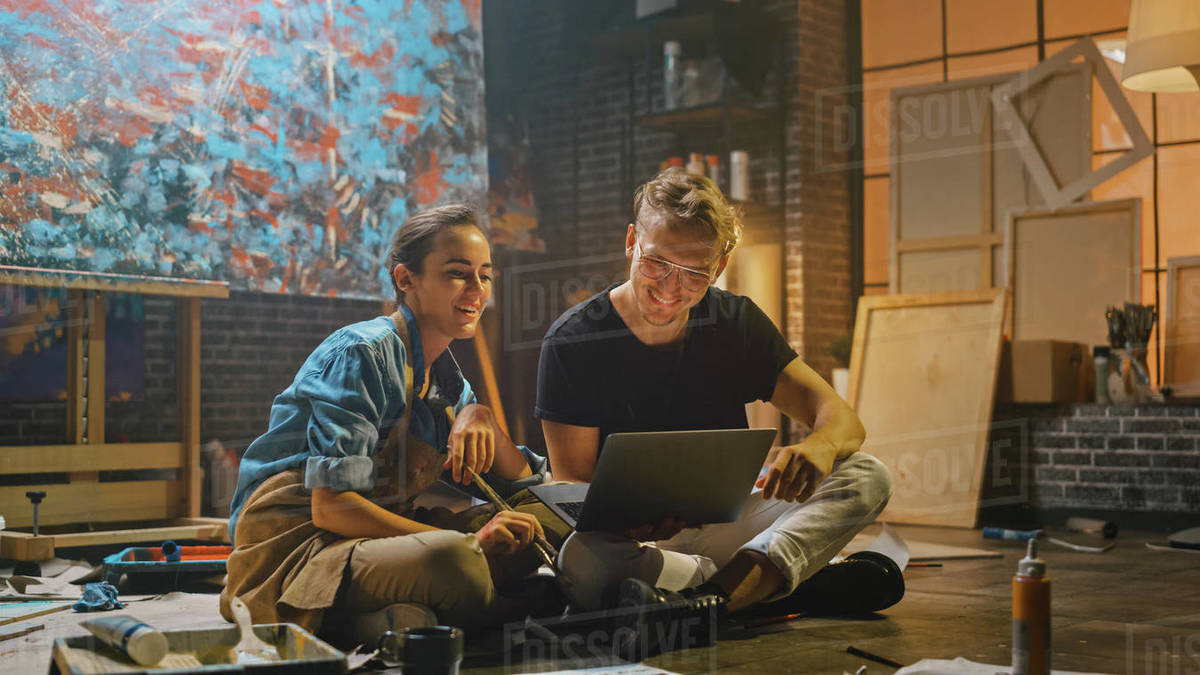 Couple of Artists Sitting in their Studio Use Laptop Computer, Working ...