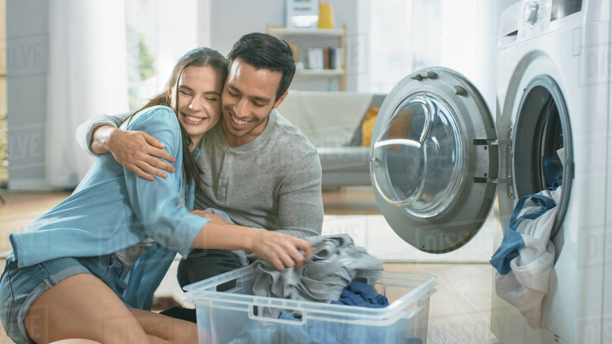 Beautiful Young Couple Sit Next to a Washing Machine at Home. They ...