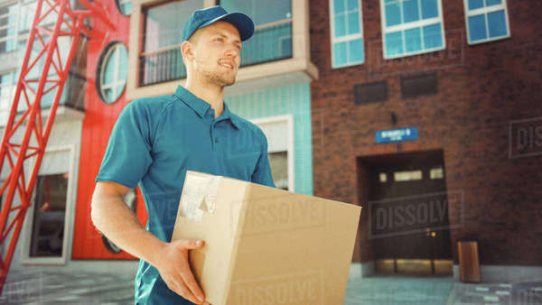 Handsome Delivery Man Holds Cardboard Box Package Walks Through Modern ...
