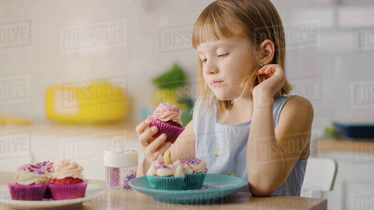 In the Kitchen: Adorable Little Girl Eats Creamy Cupcake with Frosting ...