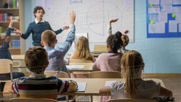 Caring Teacher Explains Lesson to a Classroom Full of Diverse Children ...
