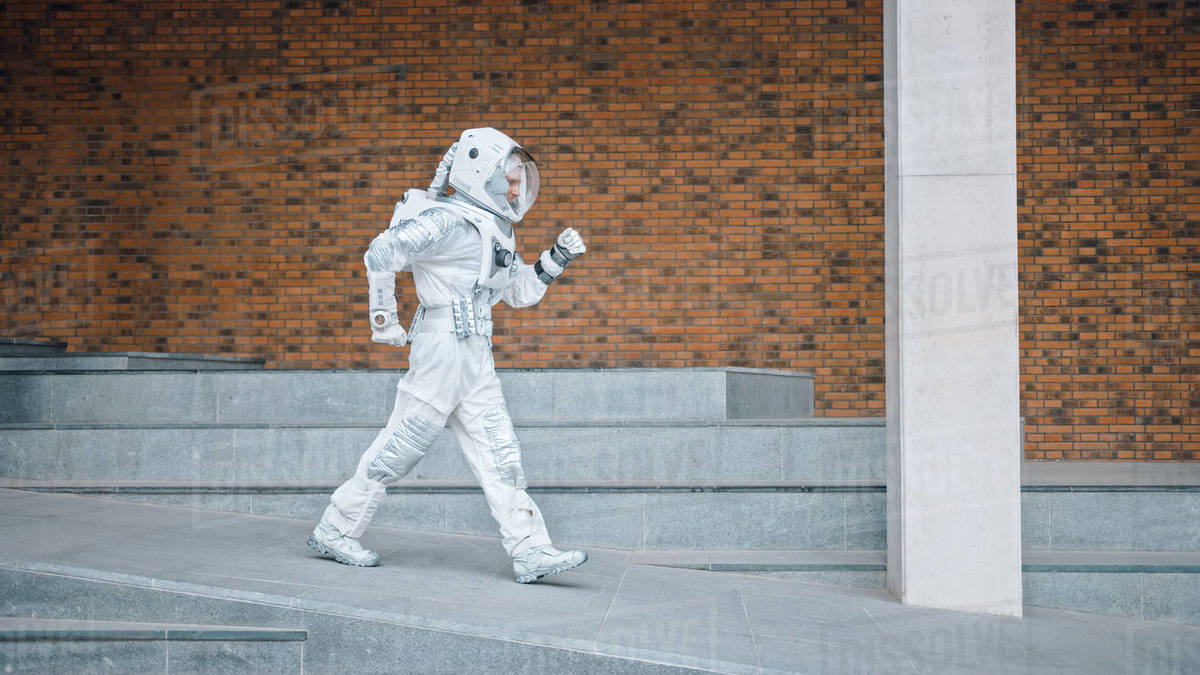 Handsome Man in Spacesuit is Dancing on Concrete Stairs. Astronaut is ...