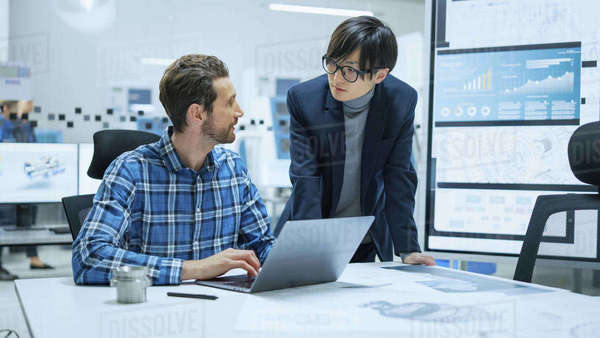 Modern Factory: Industrial Engineer Sitting at His Desk, Working on ...