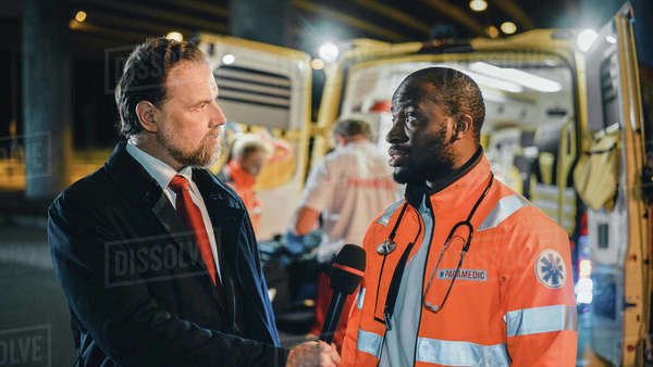 Anchorman interviews paramedic outside ambulance - Royalty-free Stock ...