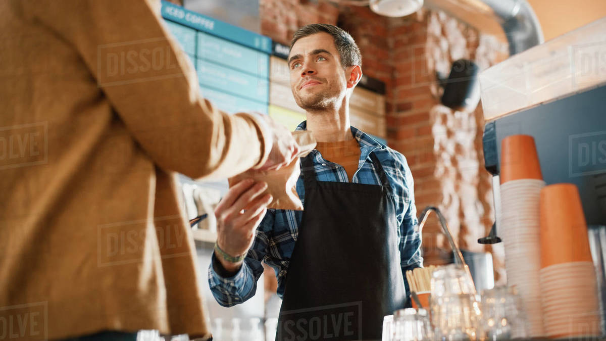 Close-up view of a barista handing over an order to a customer at a ...