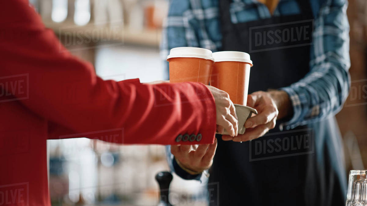 Close-up view of a barista handing over an order to a customer at a ...