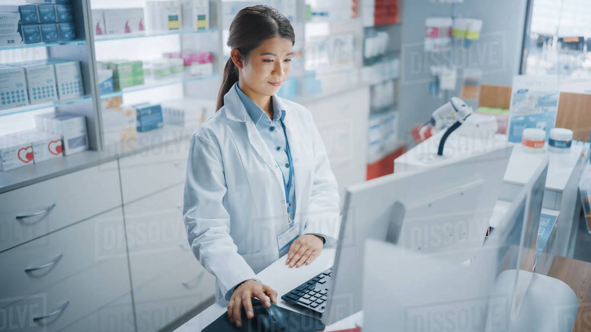 Pharmacist Uses Checkout Counter Computer - Stock Photo - Dissolve
