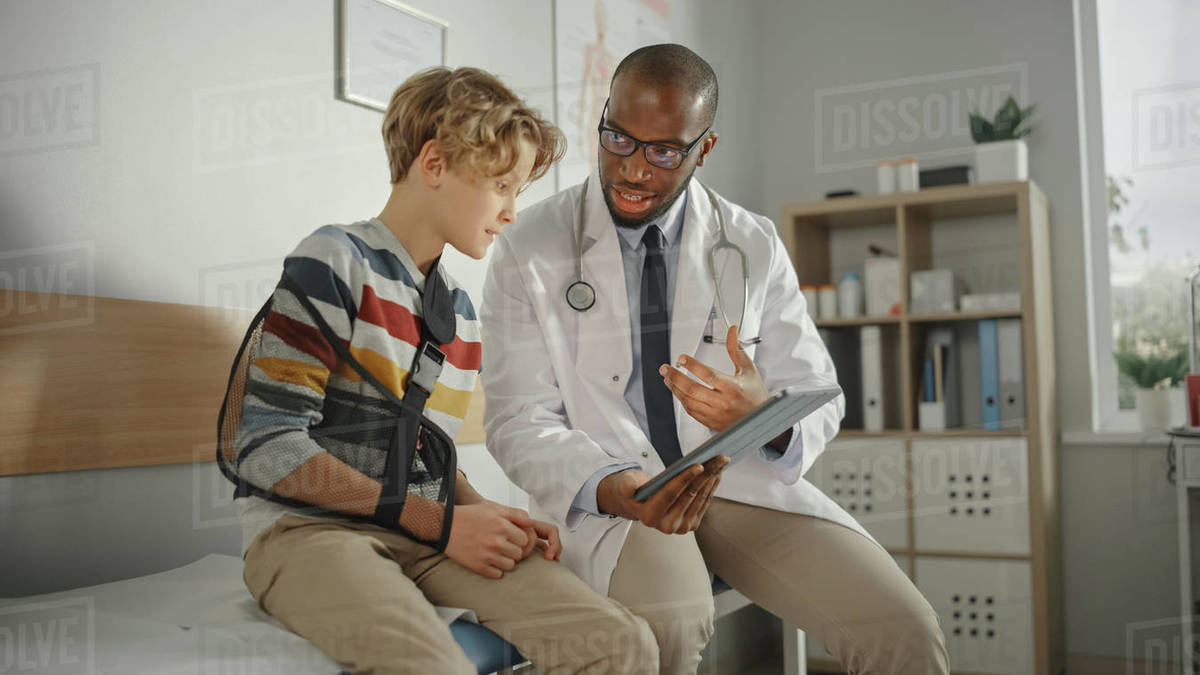 Friendly African American Family Doctor Talking with a Young Boy with ...