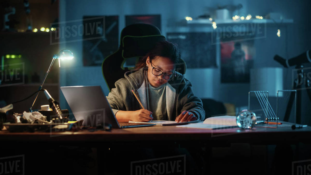 Young Teenage Black Girl Writing Down Homework in a Notebook with a ...