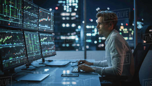 Financial Analyst Working on a Computer with Multi-Monitor Workstation ...