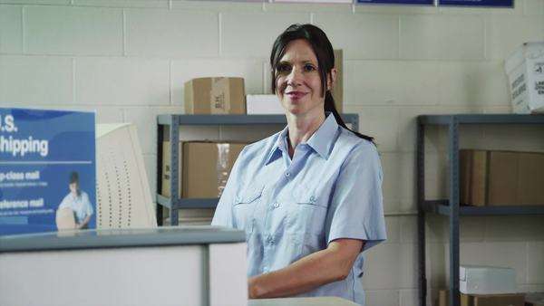 Medium shot pan of Portrait of female postal worker behind post office ...
