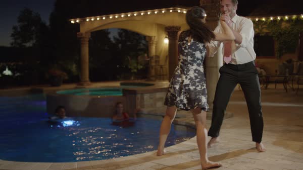 Medium panning shot of man pushing woman into pool - 4K Royalty-free ...