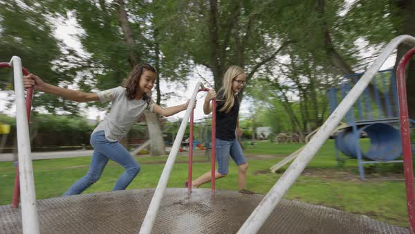 Girls pushing and riding neighborhood playground merry-go-round / Provo ...