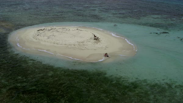 Aerial view of distant couple sitting on remote sand bar beach ...